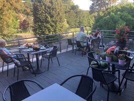 Um terraço com área de estar ao ar livre, mesas e cadeiras.