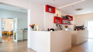 Cozinha moderna com bancadas brancas, estantes vermelhas e uma máquina de café.