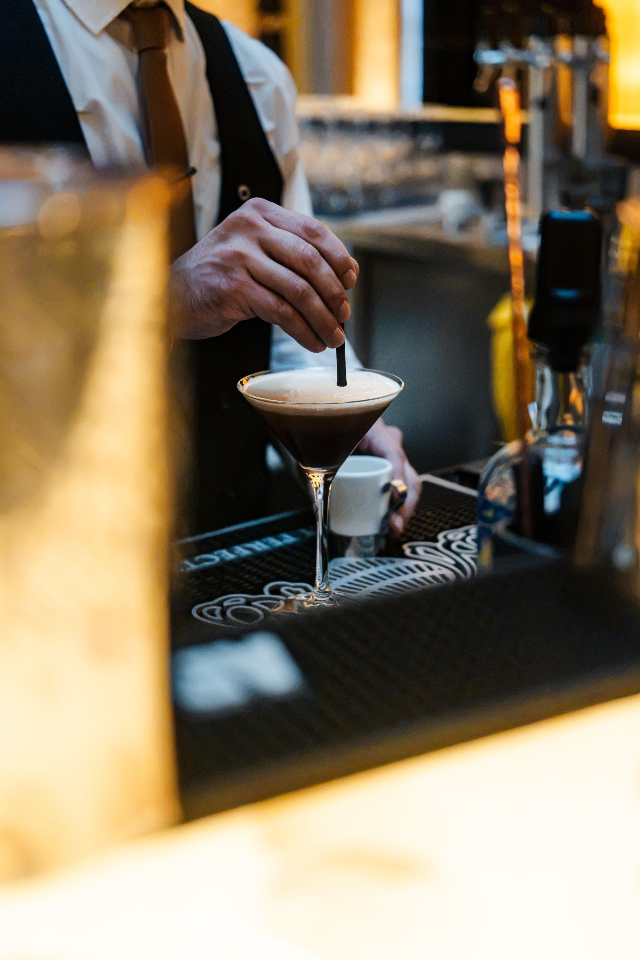 Um barista preparando uma bebida em um copo de martini.