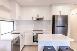 Cozinha moderna com armários brancos, eletrodomésticos de aço inoxidável e uma ilha central.
