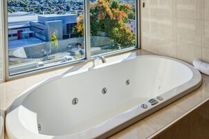 Uma banheira grande e moderna com vista para o horizonte urbano através de uma janela ampla.