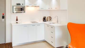 Uma cozinha moderna com armários brancos, micro-ondas, máquina de café e pia.