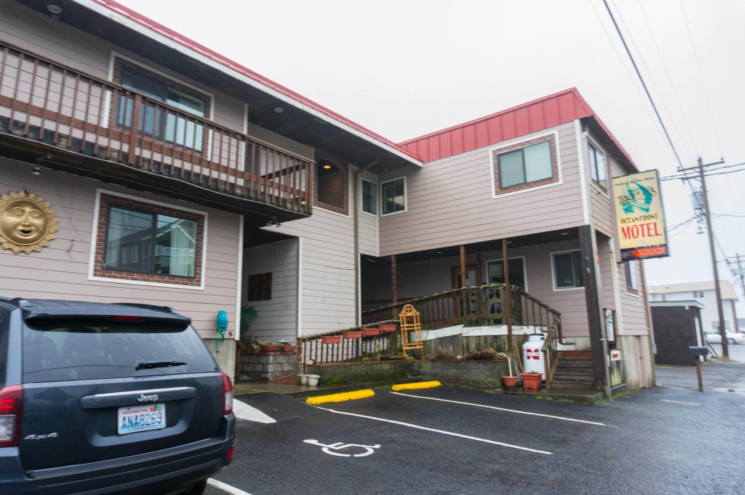 Um motel com um edifício de dois andares, uma vaga de estacionamento para deficientes visíveis e um Jeep estacionado na frente.