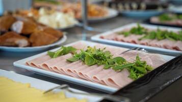 Buffet com diversos pratos, incluindo carnes fatiadas e saladas.