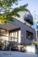 Um edifício moderno com varanda, plantas em vasos e um banco na parte externa.