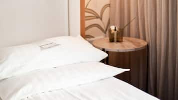Quarto de hotel com uma cama, mesa de cabeceira, abajur e cortinas.