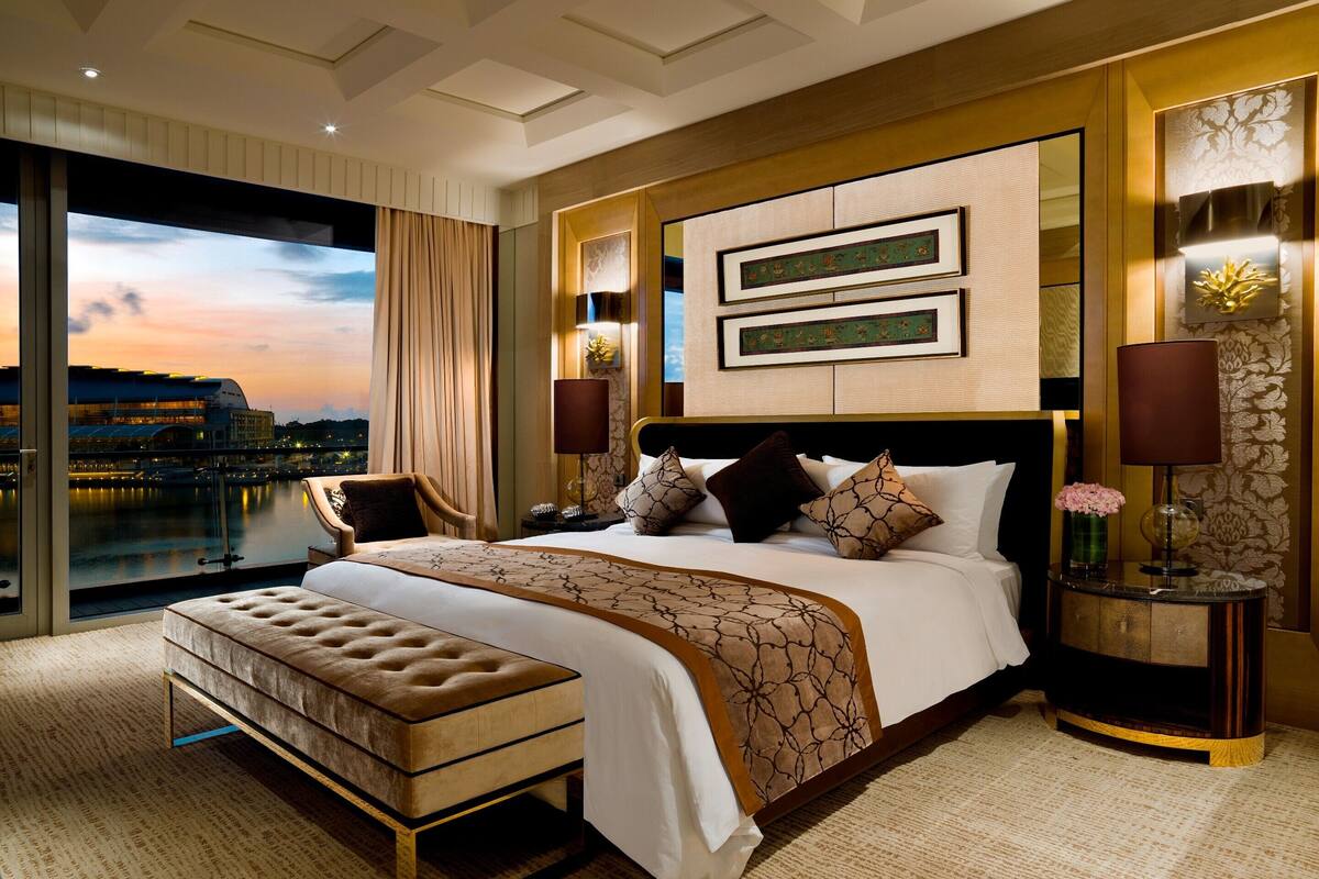 Um quarto amplo com uma cama grande, um espaço de estar e vista para a paisagem urbana.