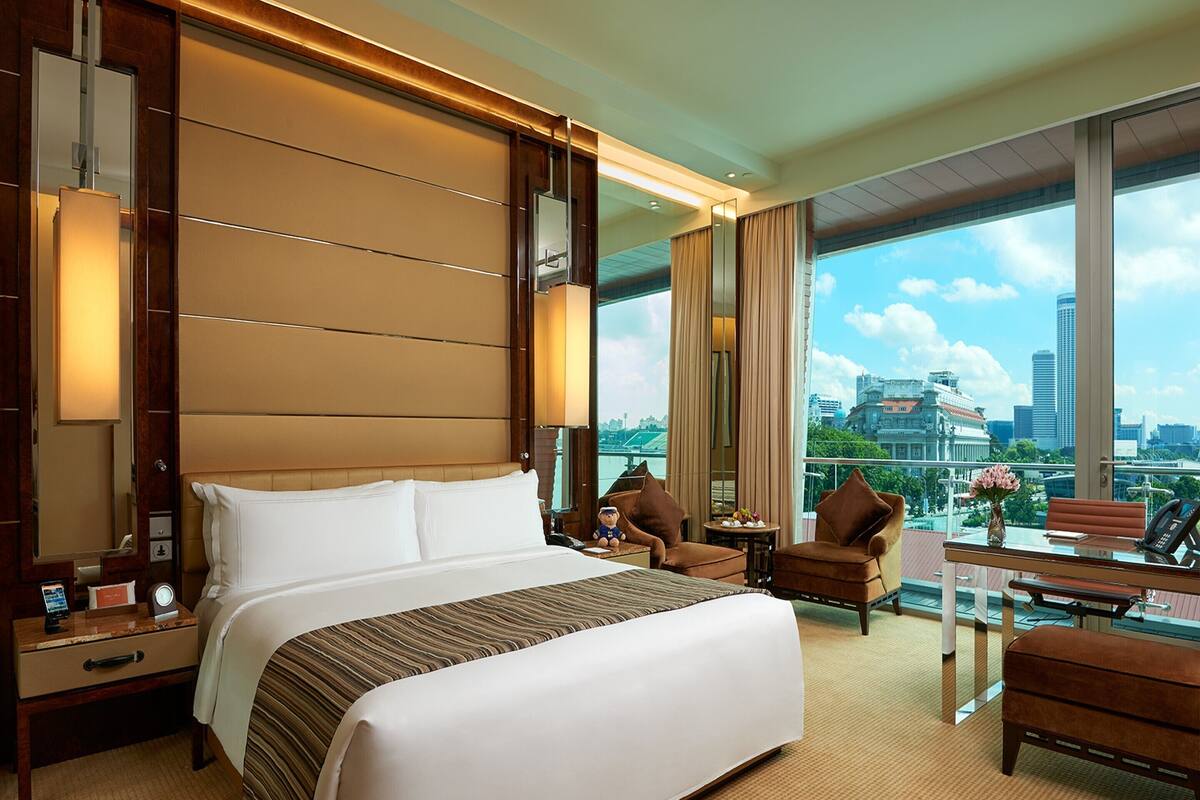 Quarto de hotel com uma cama grande, uma escrivaninha, uma cadeira e vista para a cidade.