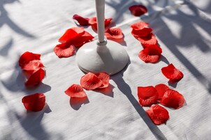 Uma toalha branca com pétalas de rosas vermelhas espalhadas.