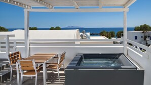 Terraço no telhado com hidromassagem, móveis de madeira e vista ampla do mar e montanhas ao longe.