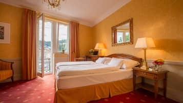 Quarto de hotel com duas camas, um candelabro, um espelho grande e vista para o exterior.