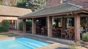 Uma casa de tijolos com piscina, pátio e área de estar ao ar livre.