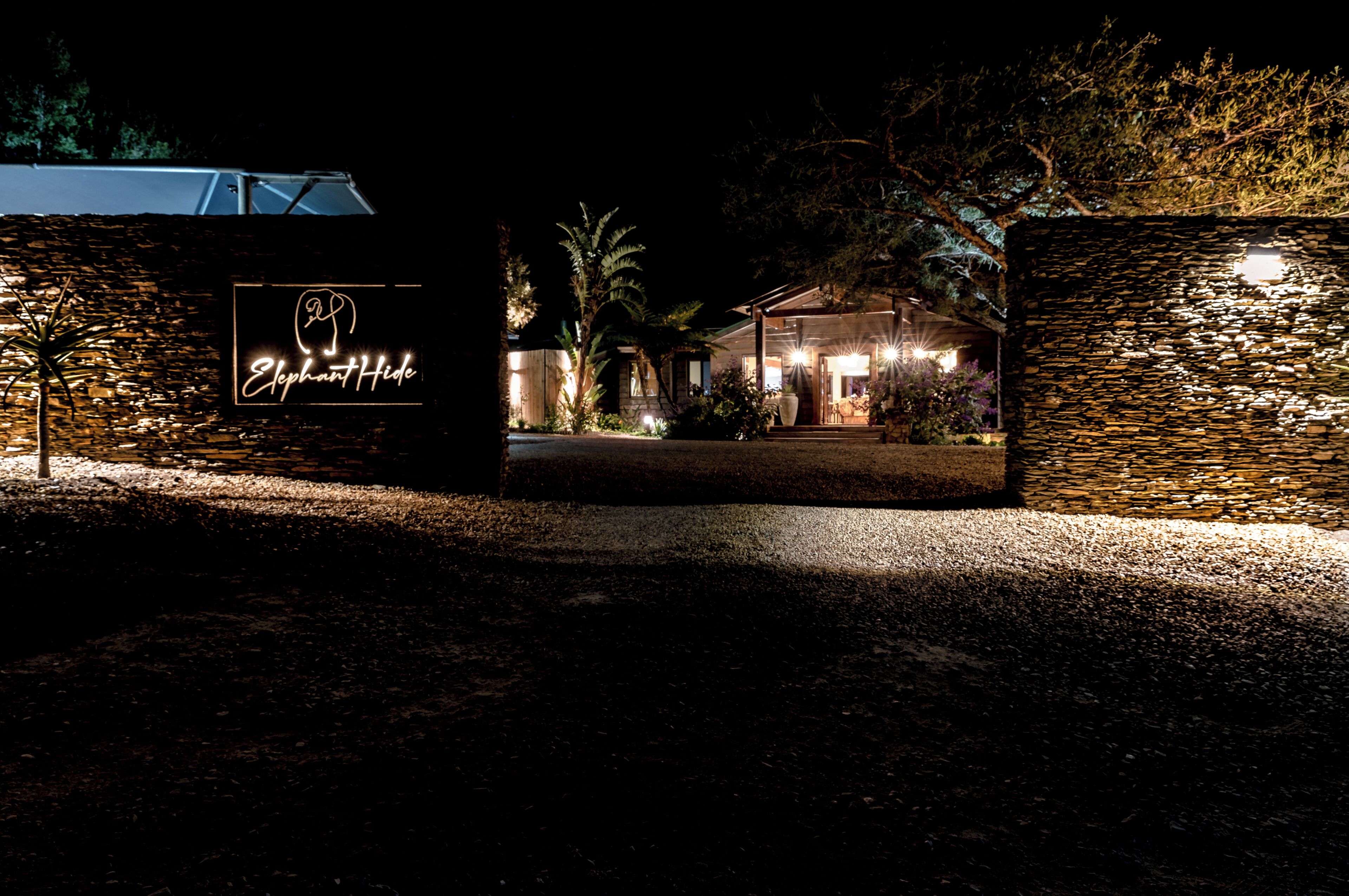 Entrada com muro de pedra e letreiro de neon para 'Elephant Hide'.