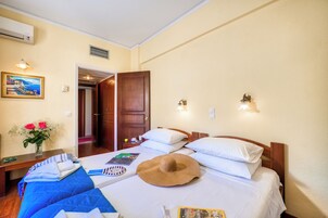 Quarto de hotel com cama, mesas de cabeceira, luminária na parede e uma pintura.