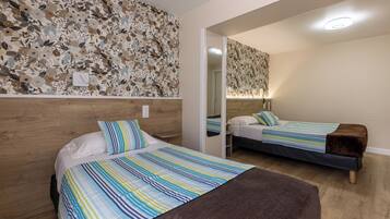 Quarto com duas camas, cabeceira de madeira, parede com padrão floral e um espelho refletindo o ambiente.