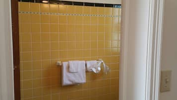 Um banheiro com azulejos amarelos, pia branca e um porta-toalhas com duas toalhas.