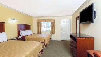 Quarto de hotel com duas camas, televisão, cômoda e porta.