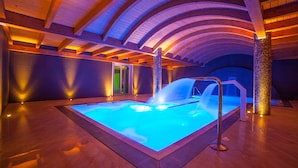 Piscina interior aquecida com piso de madeira e teto alto em arco.