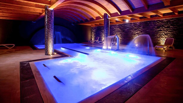 Uma área de spa com hidromassagem, duas cascatas e espreguiçadeiras.