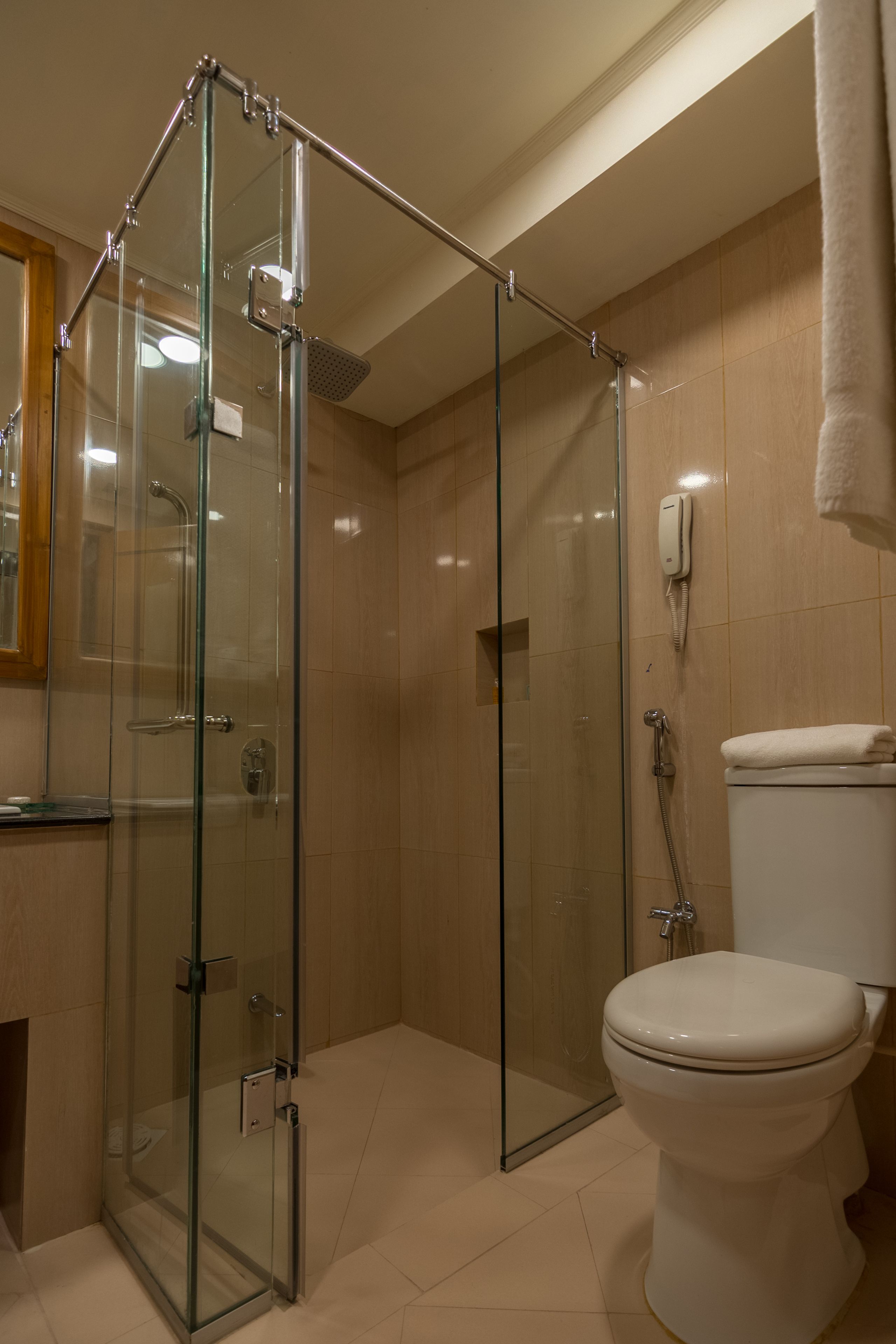 Uma casa de banho moderna com cabine de duche em vidro, sanita e secador de mãos.