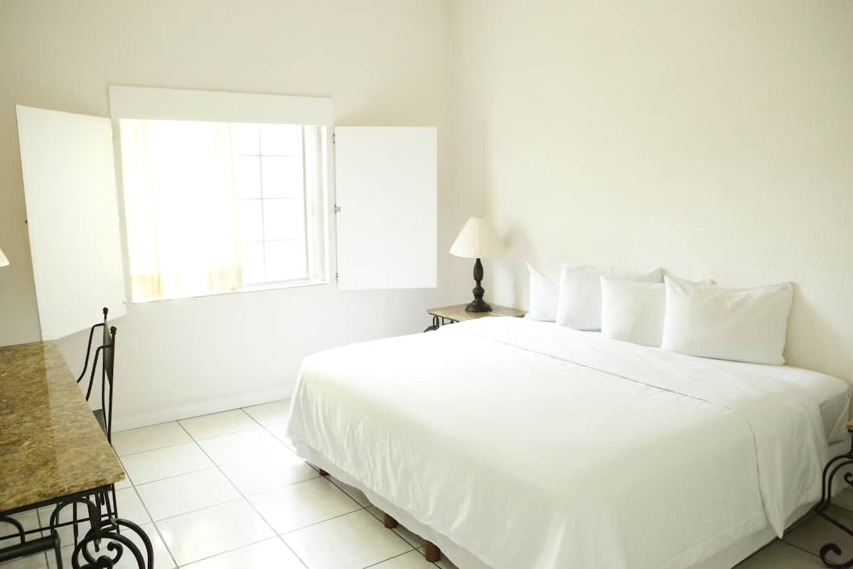 Um quarto com uma cama, uma mesa e uma janela.