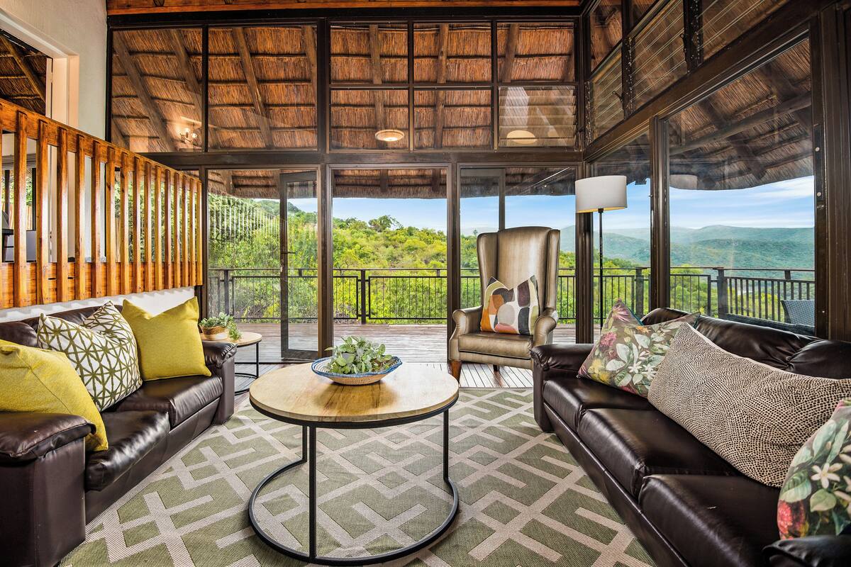 Um quarto espaçoso com teto alto, janelas amplas e vista para vegetação exuberante.