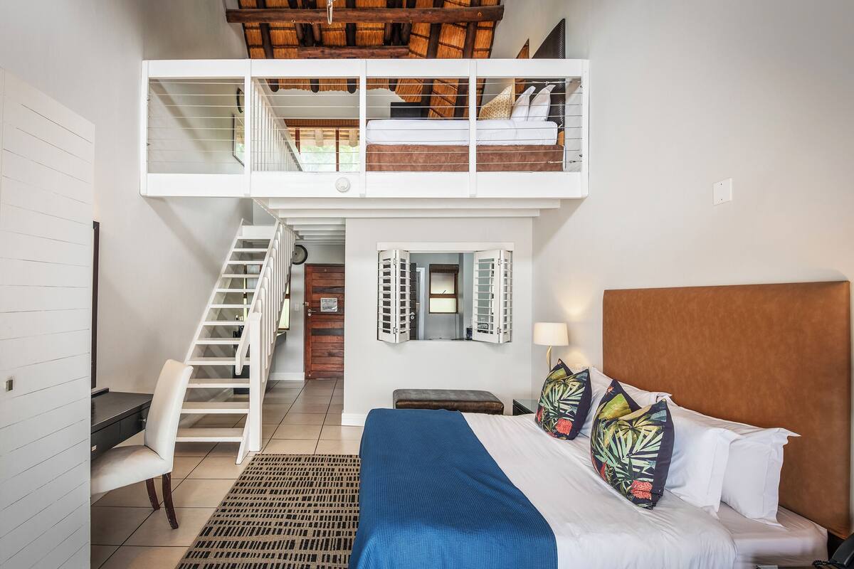 Quarto de dois andares com uma cama beliche, uma escrivaninha e uma cadeira.