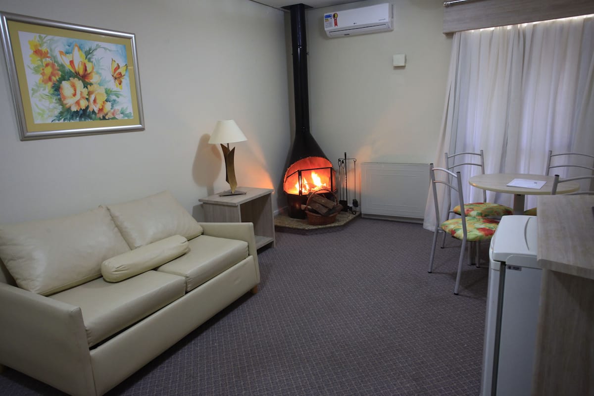 Uma sala de estar com sofá, mesa e cadeiras, lareira e ar-condicionado.
