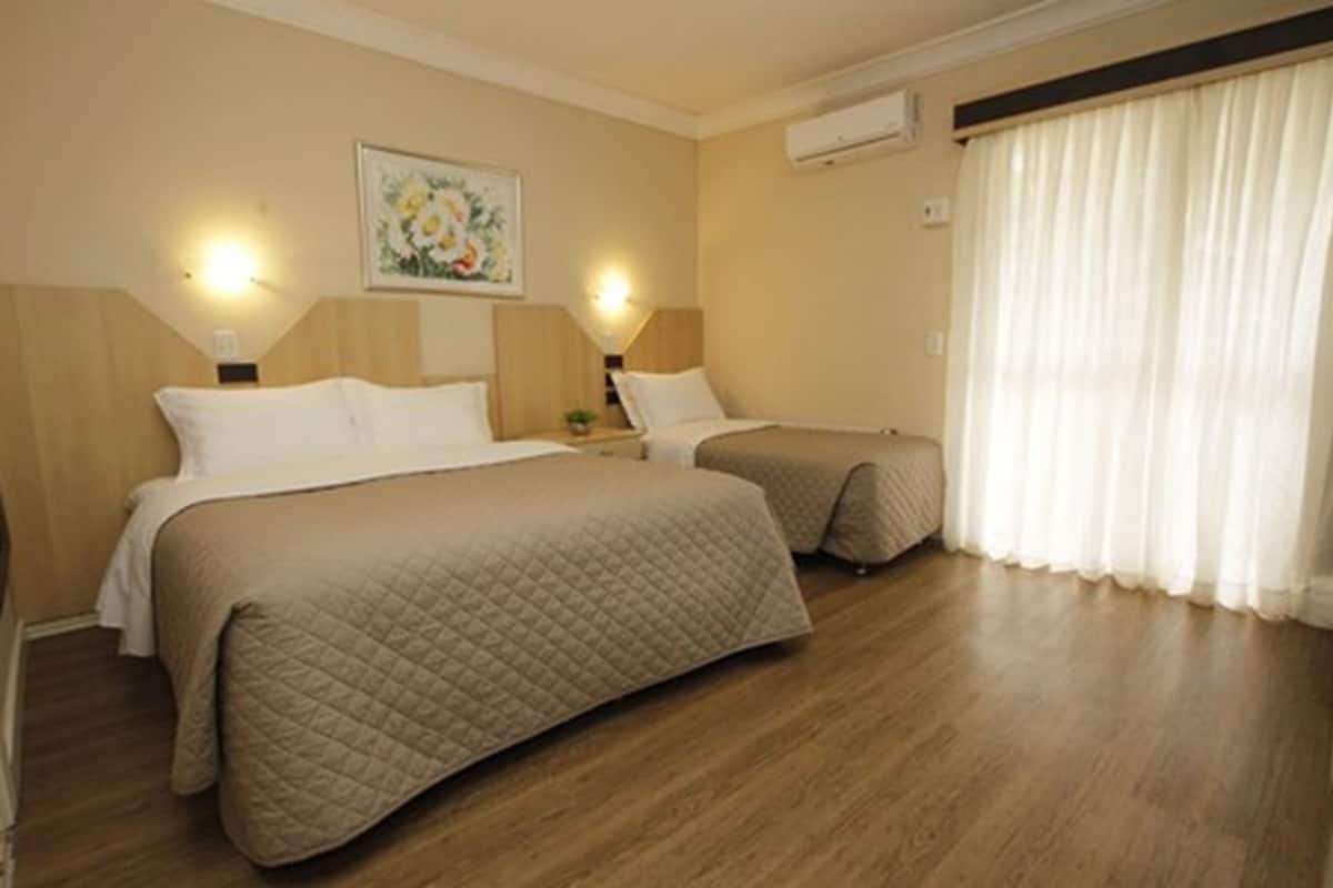 Quarto de hotel com duas camas, um quadro na parede e um aparelho de ar condicionado.