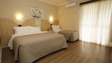 Quarto de hotel com duas camas, um quadro na parede e um aparelho de ar condicionado.