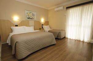 Quarto de hotel com duas camas, um quadro na parede e um aparelho de ar condicionado.