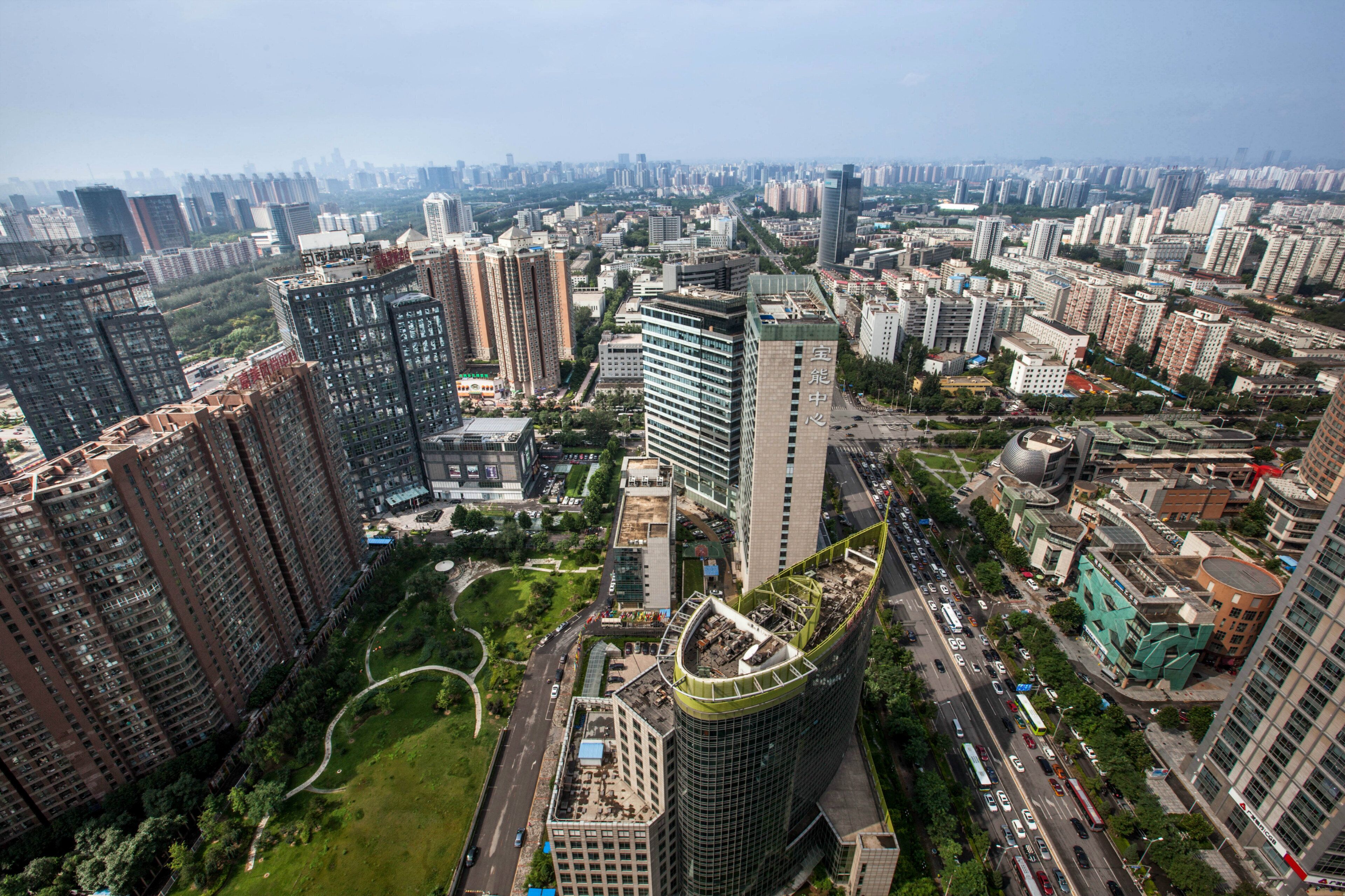 Um edifício alto com vários andares, rodeado por outros edifícios altos, ruas e áreas verdes.