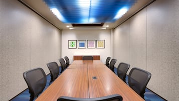 Uma sala de conferências com uma longa mesa de madeira, seis cadeiras e teto decorado.