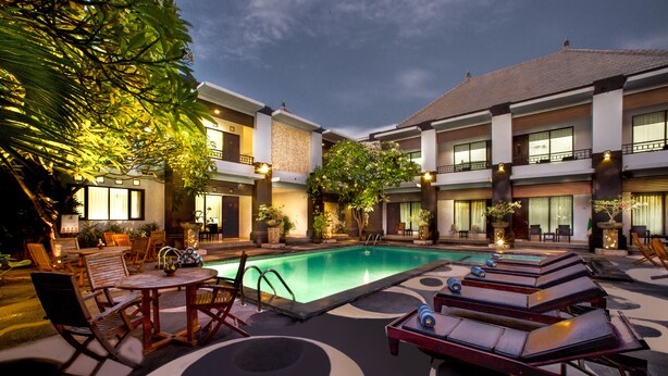 Uma área à beira da piscina com espreguiçadeiras, uma mesa e piscina.