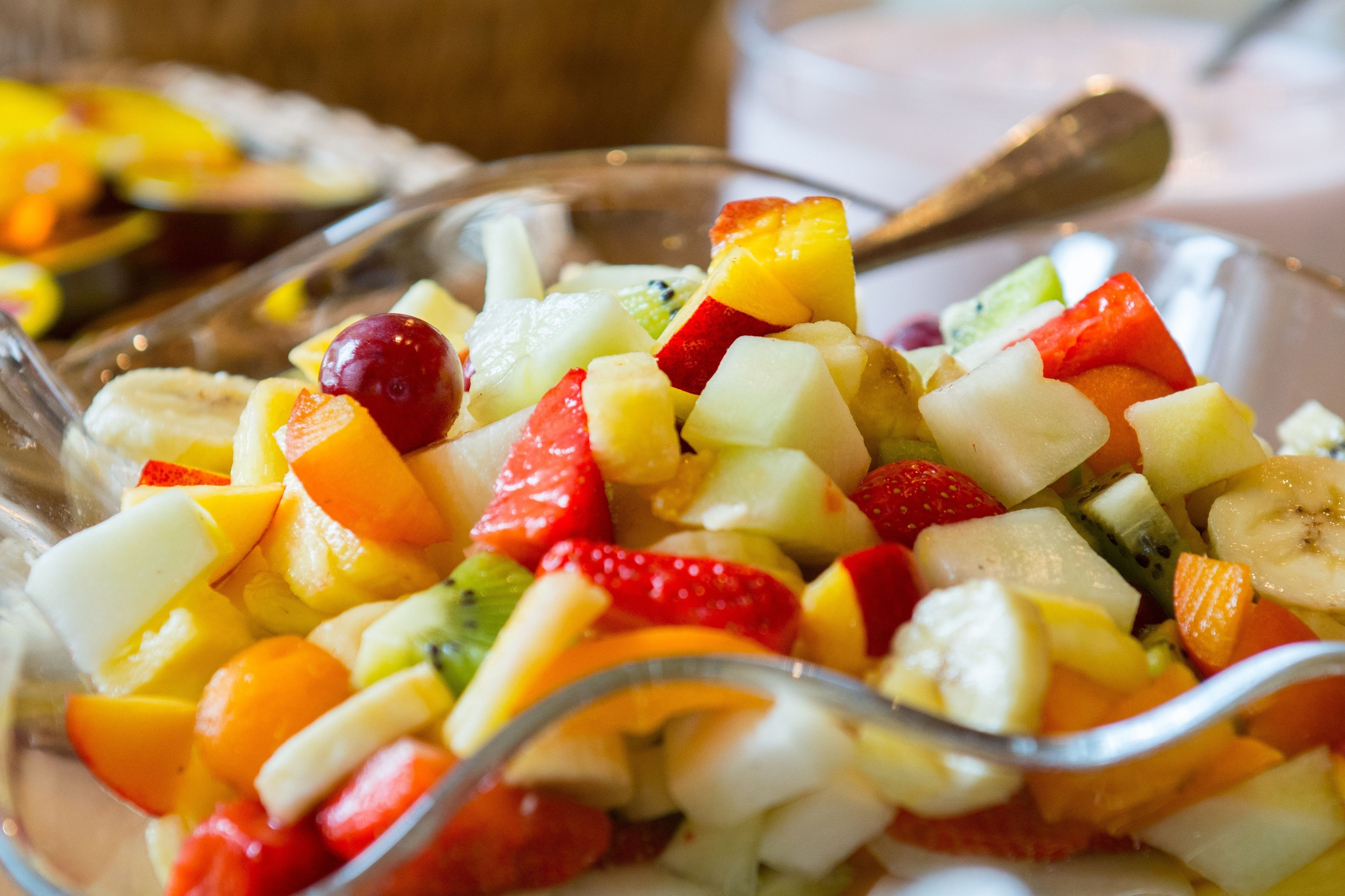 Uma tigela de vidro cheia de uma salada de frutas colorida.
