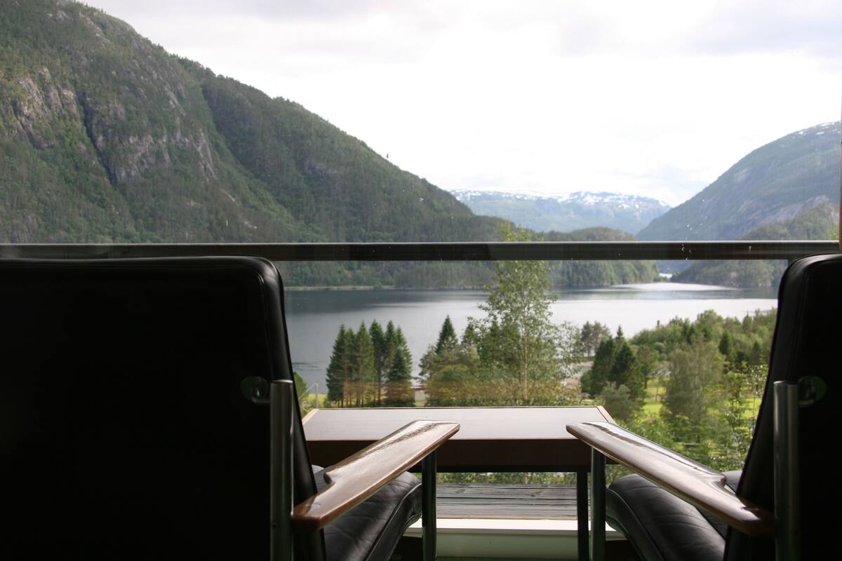 Vista de varanda com vista para um lago e montanhas ao fundo.