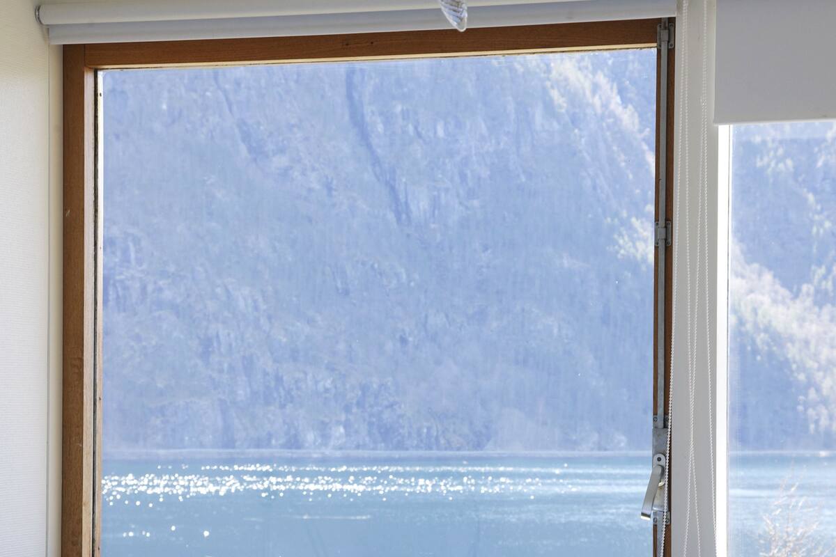 Quarto com cama, janela com vista para paisagem nevada e ventilador de teto.