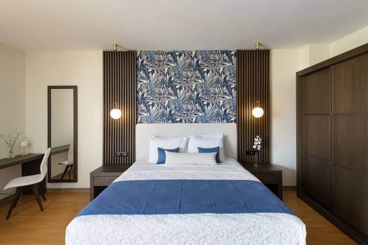 Quarto com cama, escrivaninha, cadeira, espelho e guarda-roupa.