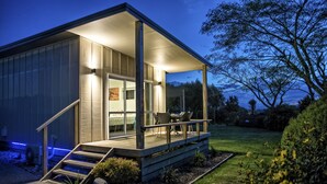 Uma casa moderna com varanda coberta, escadaria e um jardim bem cuidado.