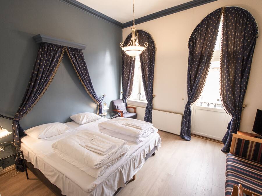 Quarto com cama, cadeira, escrivaninha e televisão.