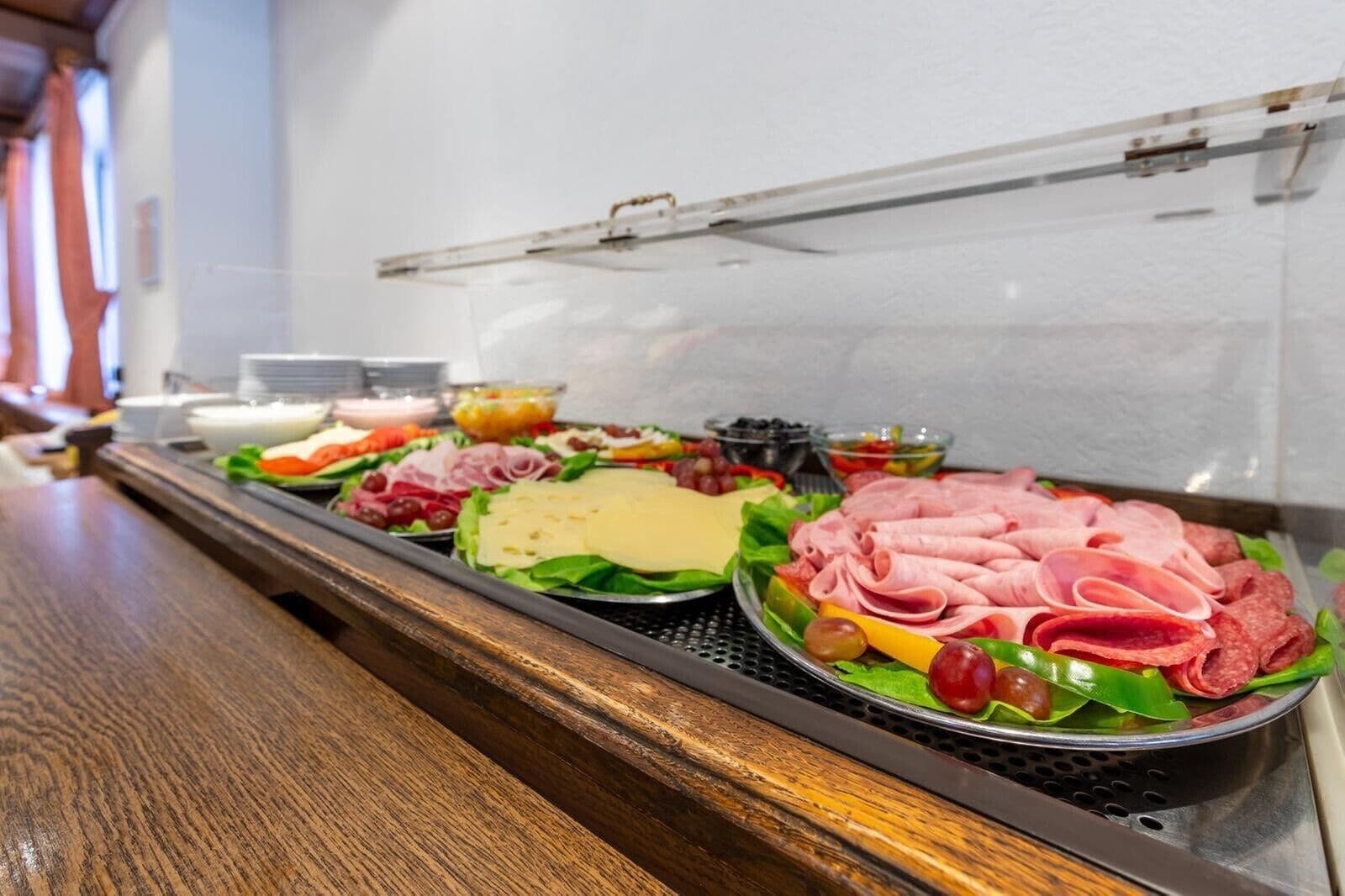 Buffet com diversos alimentos, incluindo carnes, queijos e vegetais.