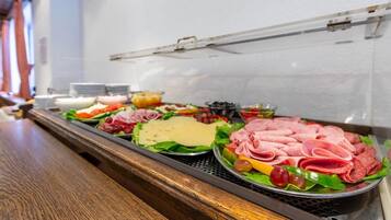 Buffet com diversos alimentos, incluindo carnes, queijos e vegetais.