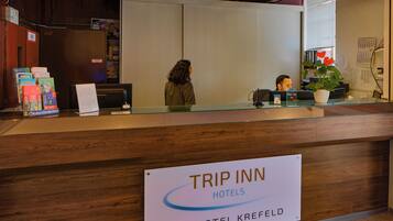 Bancada de recepção no Cityhotel Krefeld com uma placa indicando ser um hotel Trip Inn.