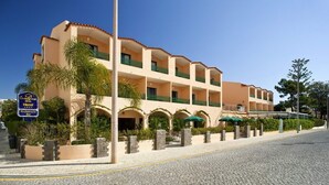 Hotel com várias varandas, um bar-restaurante e uma rua de calçada.