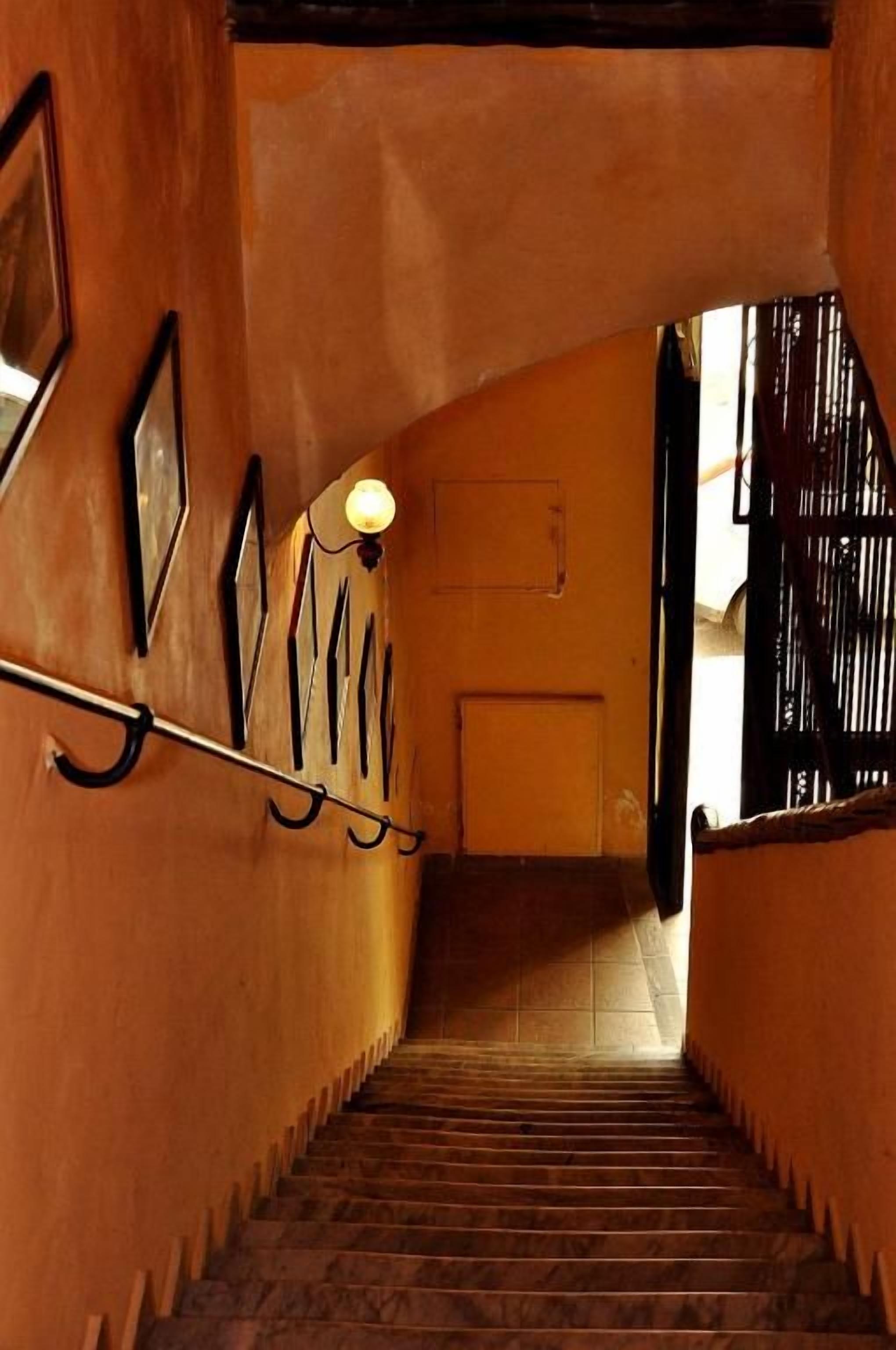 Uma escada com corrimão, luminária e porta no topo.