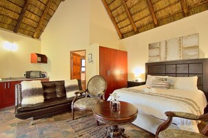 Quarto de hotel com cama, sofá, mesa de jantar e cozinha.