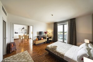 Quarto de hotel com cama, escrivaninha, cadeira, televisão e vista para o exterior.