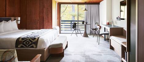 Quarto de hotel com uma cama grande, uma escrivaninha, uma cadeira e vista para o exterior.