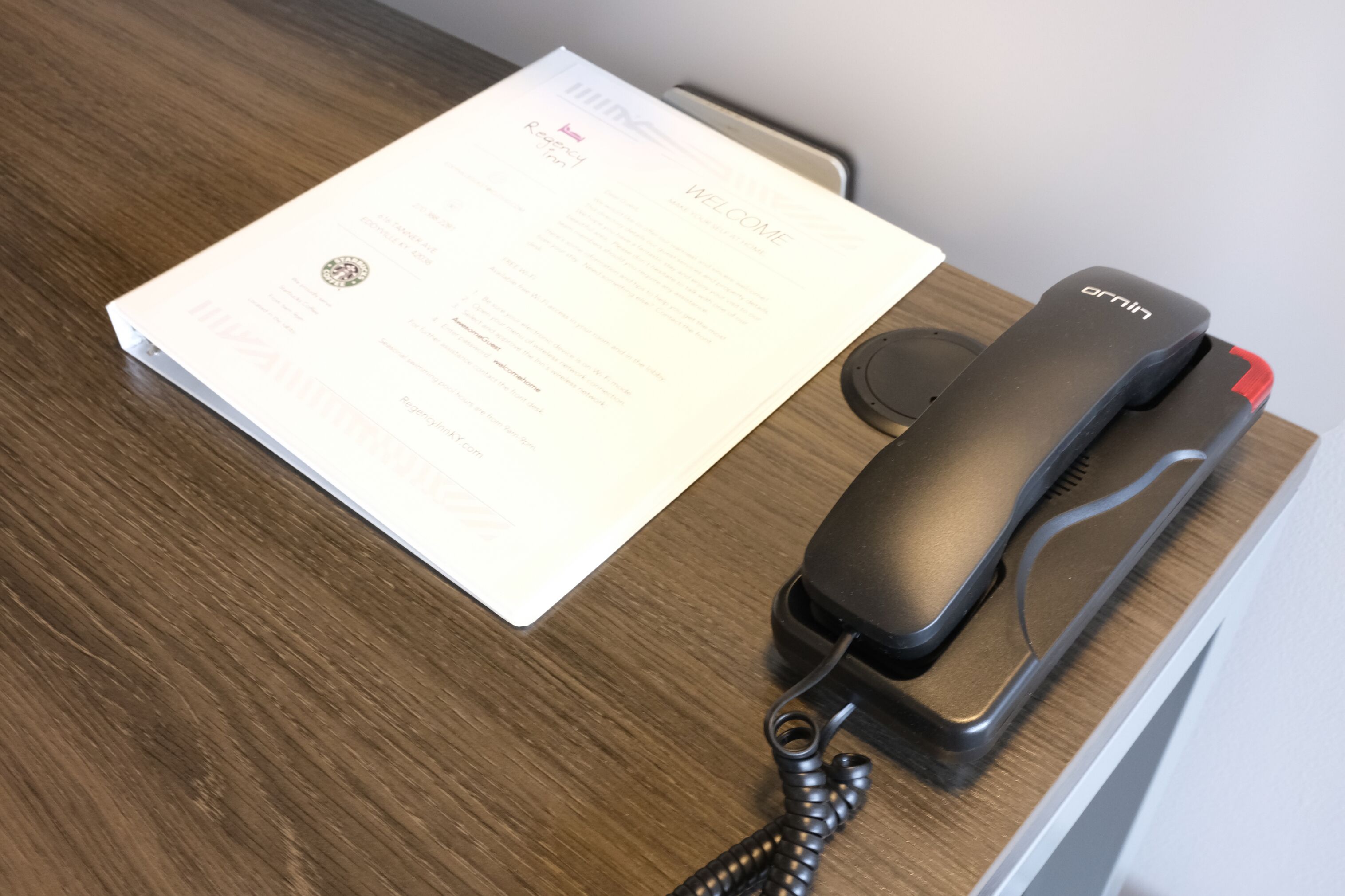 Uma mesa com um telefone preto e uma carta de boas-vindas.
