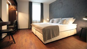 Quarto de hotel moderno com uma cama grande, uma mesa e uma cadeira.